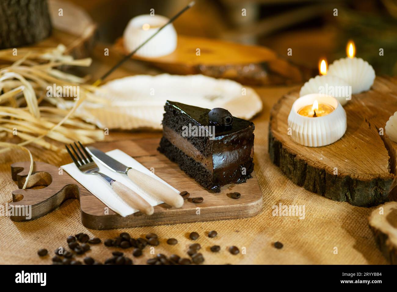 A slice of chocolate cake elegantly presented with cutlery, candles ...