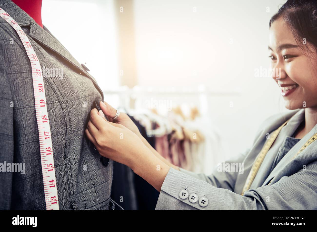 Asian female fashion designer girl making fit on the formal suit ...