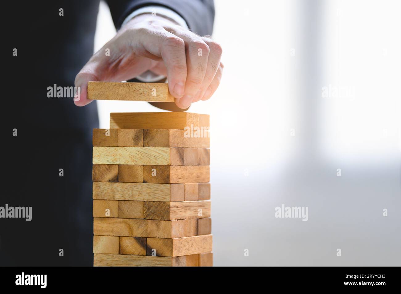 Businessman arranging wood block and stacking as tower by hand ...