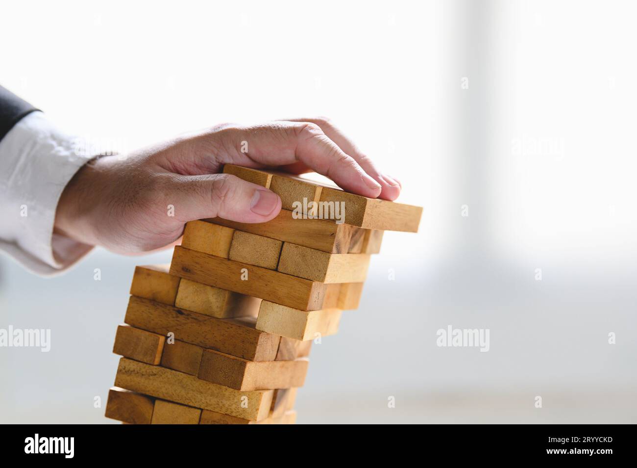 Businessman collapsing stacked tower wood block by hand as failure or ...