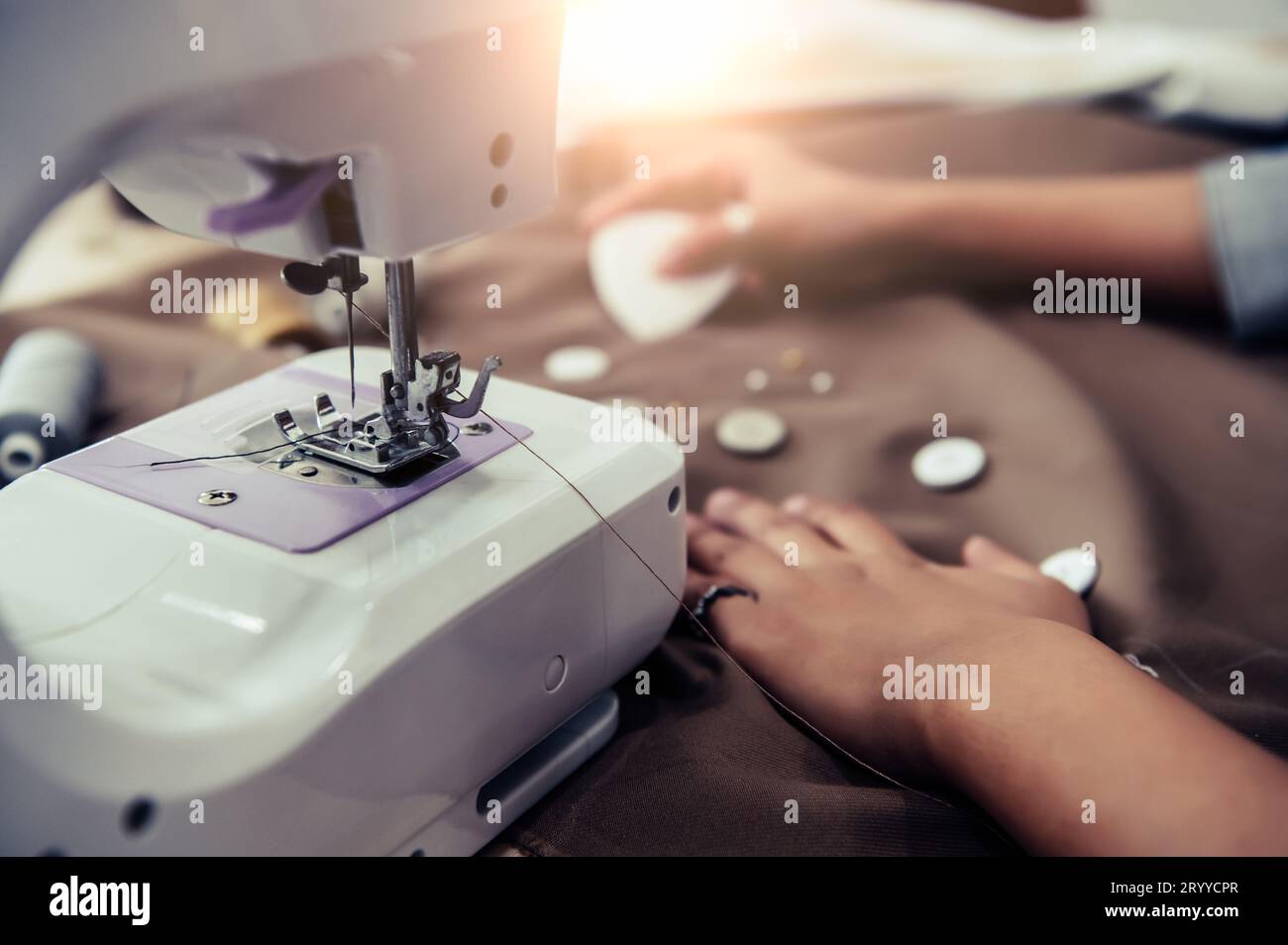 Closeup of sewing machine with dressmaker designing new fashion dress ...