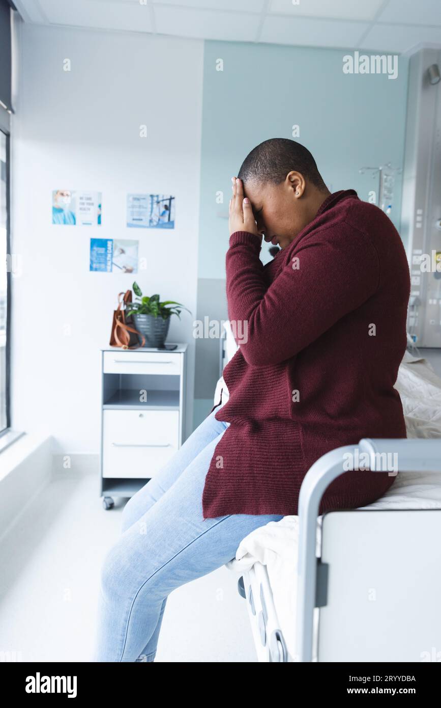Sad african american female patient sitting on bed and crying in ...