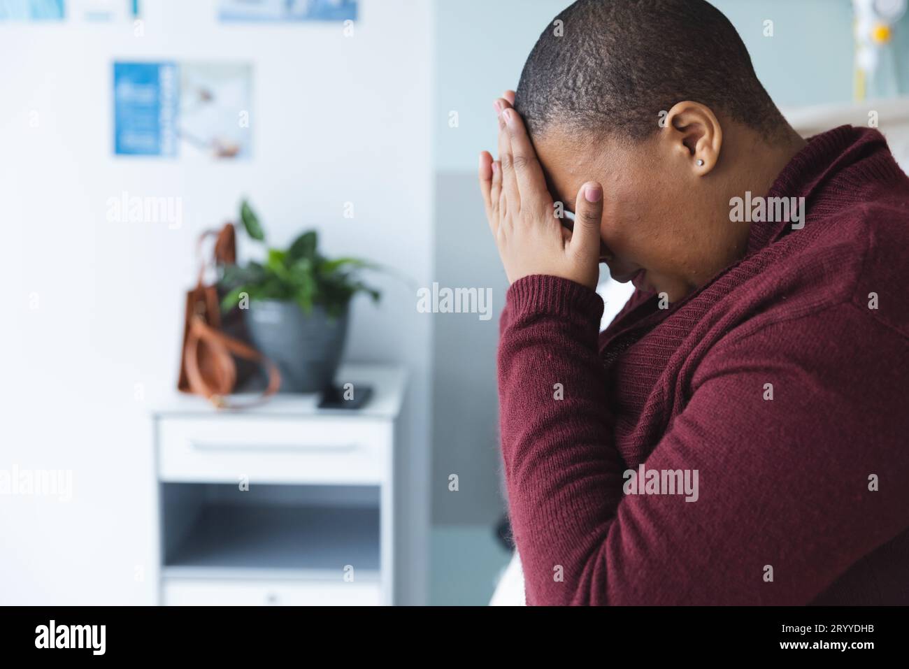 Sad african american female patient sitting on bed and crying in ...