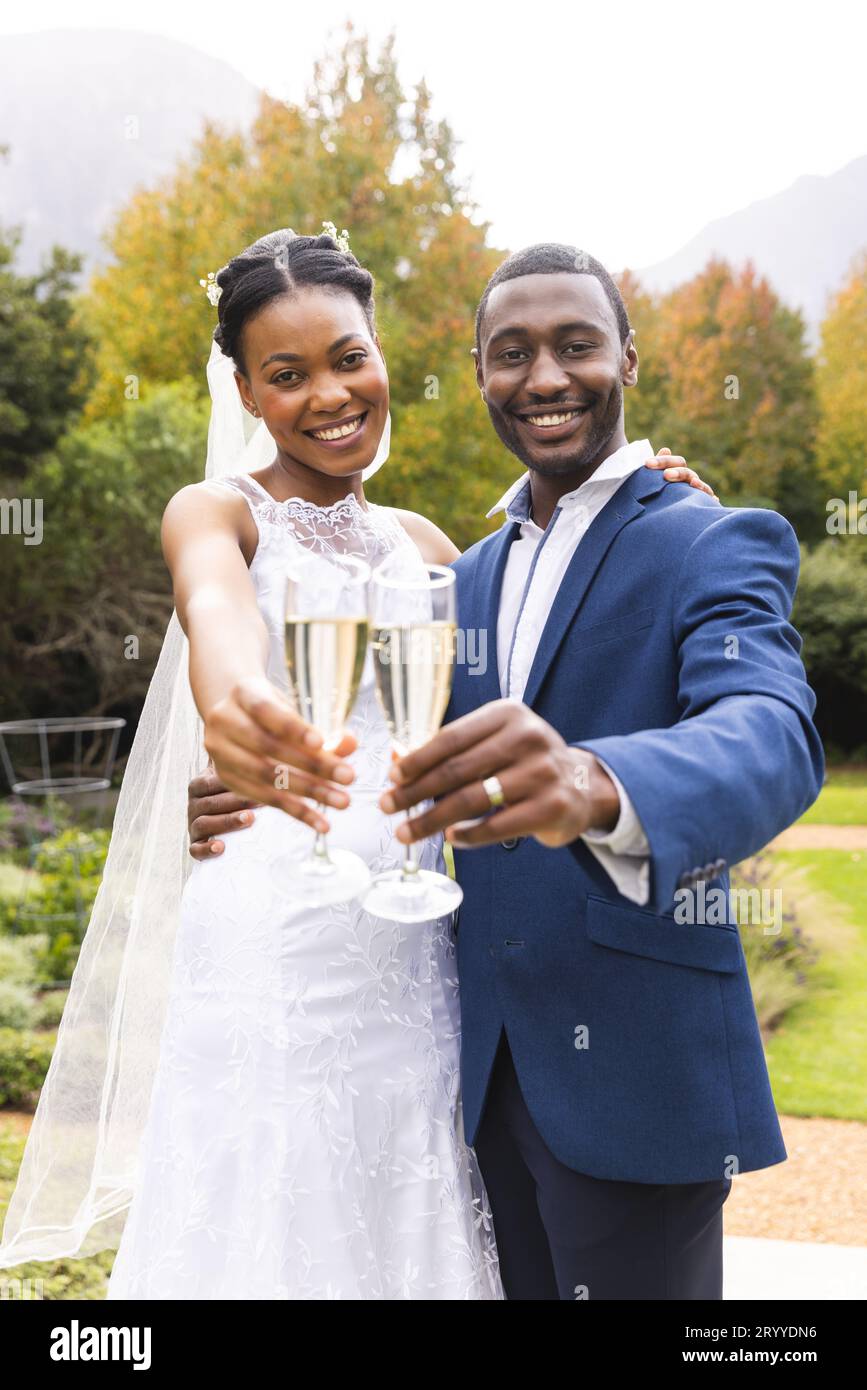 Portrait of happy african american bride and groom toasting with ...