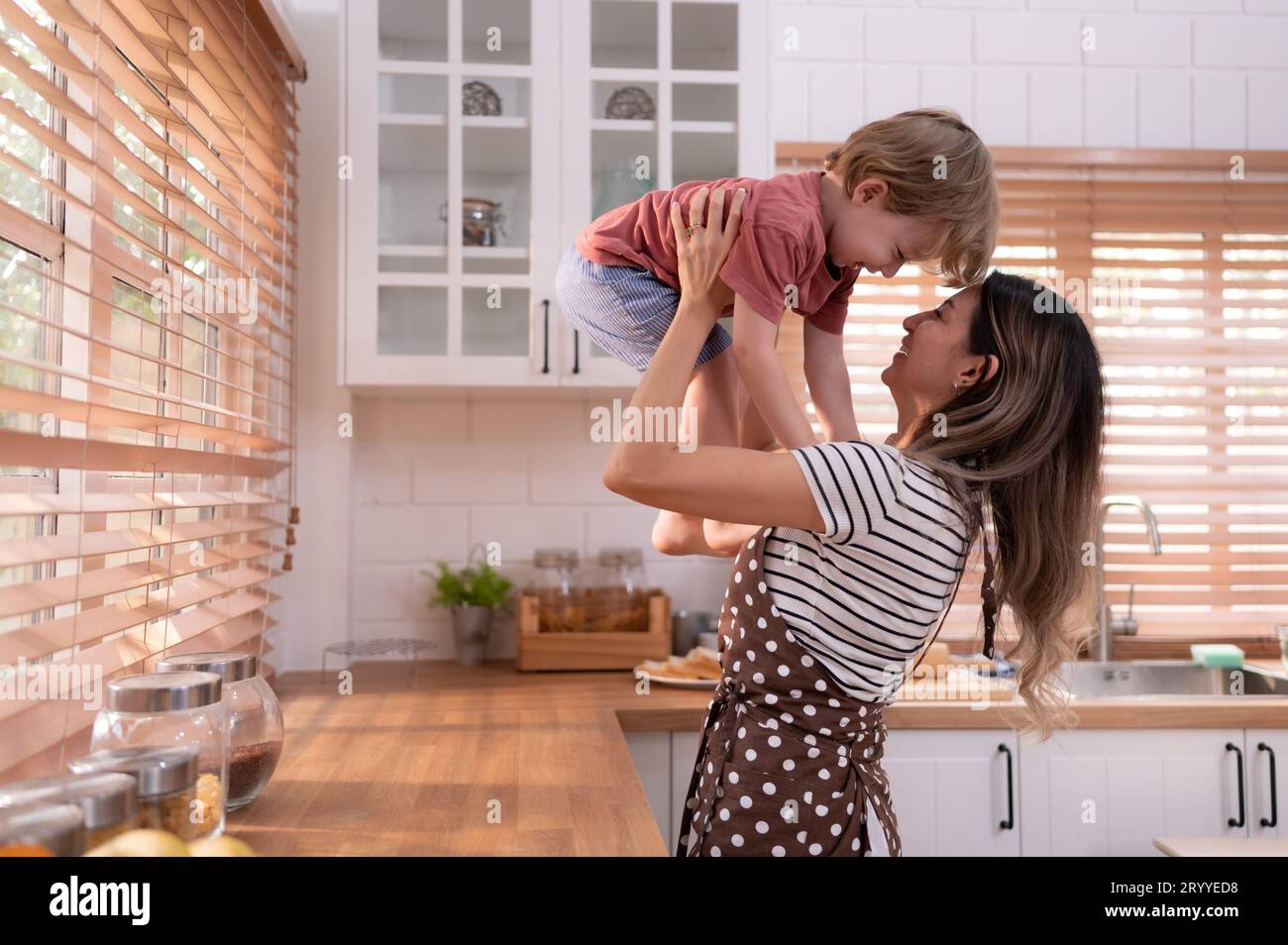 Mother in the kitchen of the house with a small child. Play and have ...