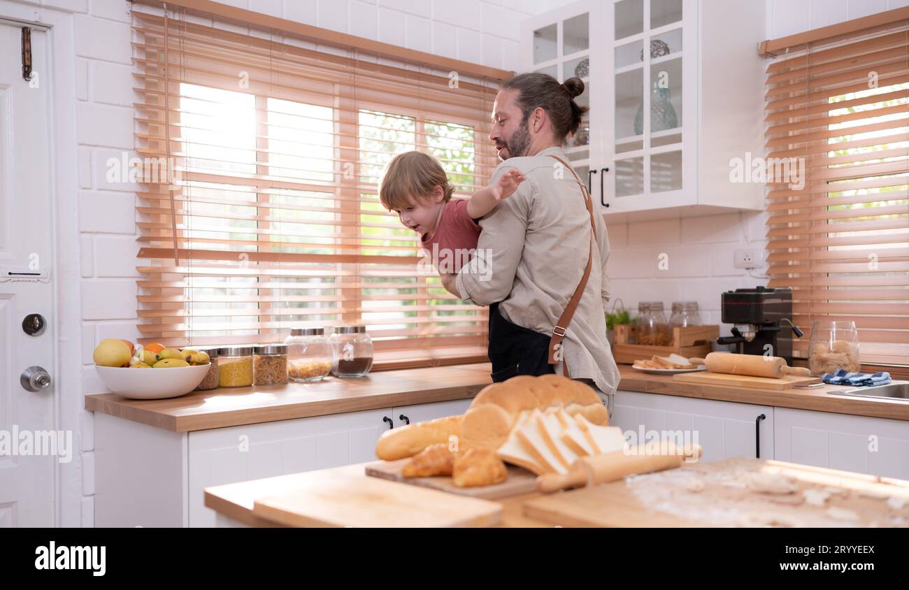 Father in the kitchen of the house with a small child. Play and have ...