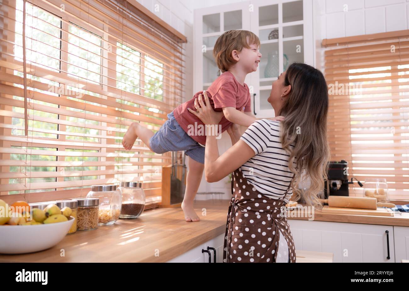 Mother in the kitchen of the house with a small child. Play and have ...