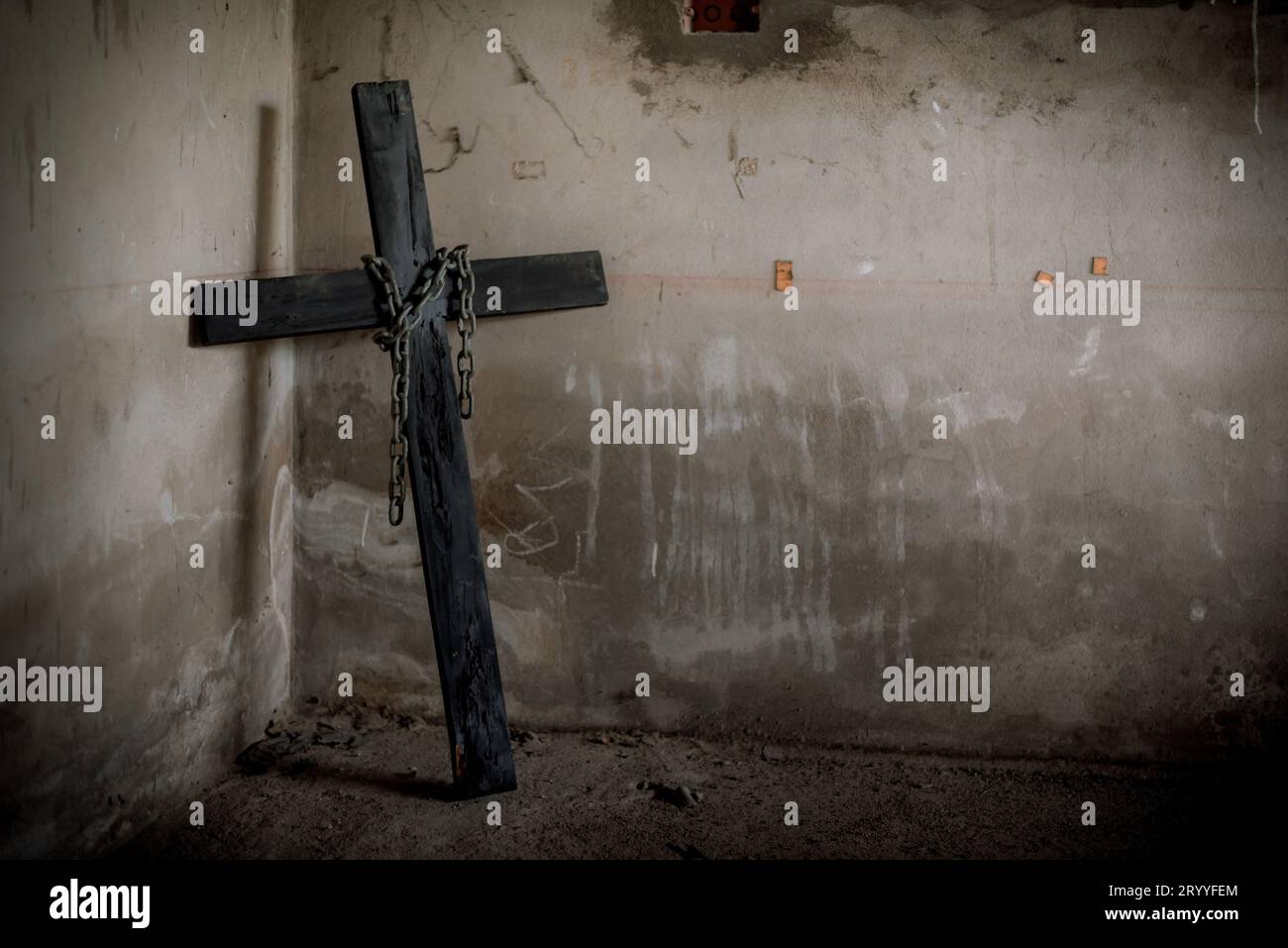 Black crucifix against wall with hanging steel chain and gun. Halloween ...