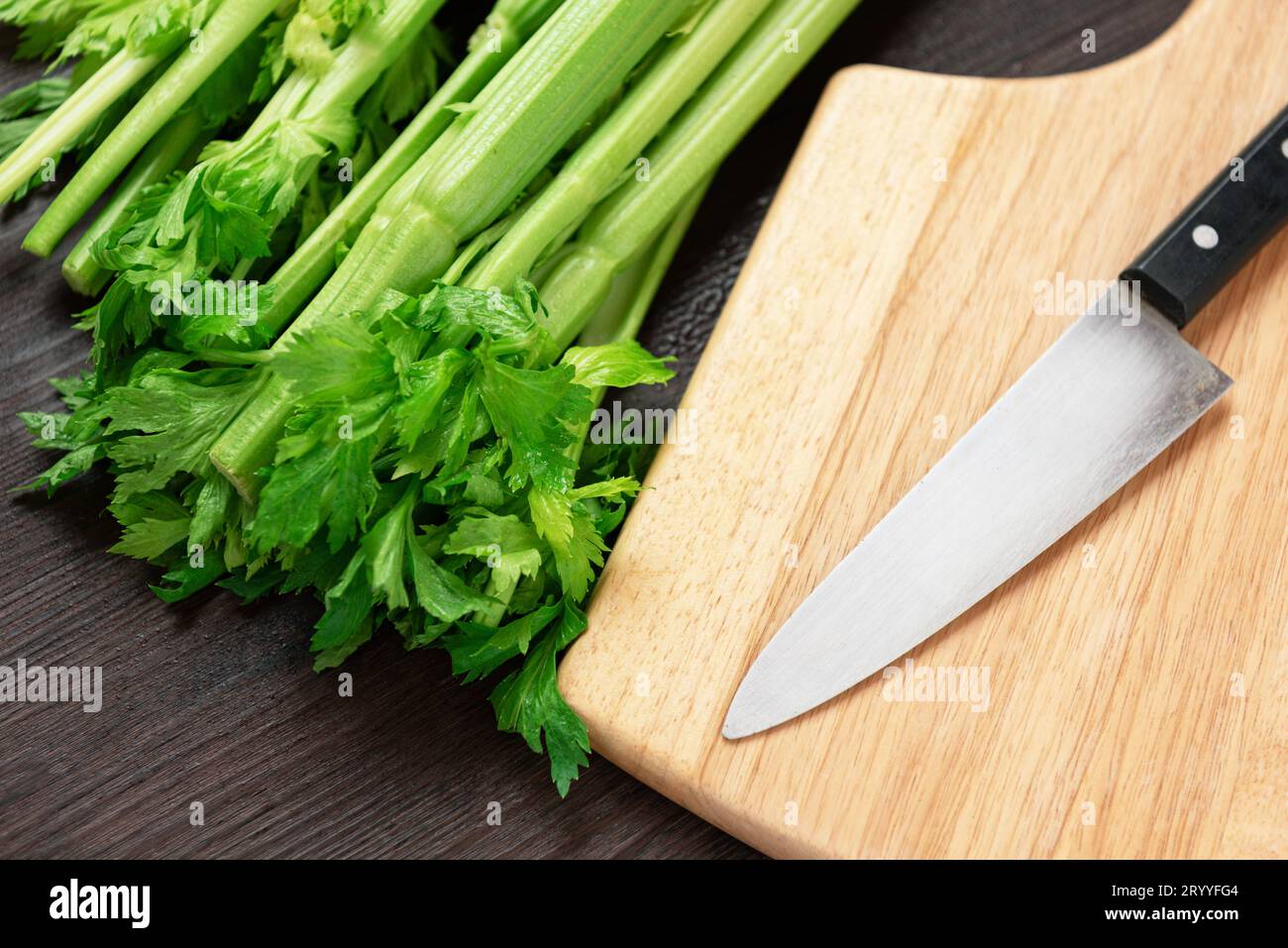 Bunch of fresh celery stalk on wooden table and cutting board and knife ...