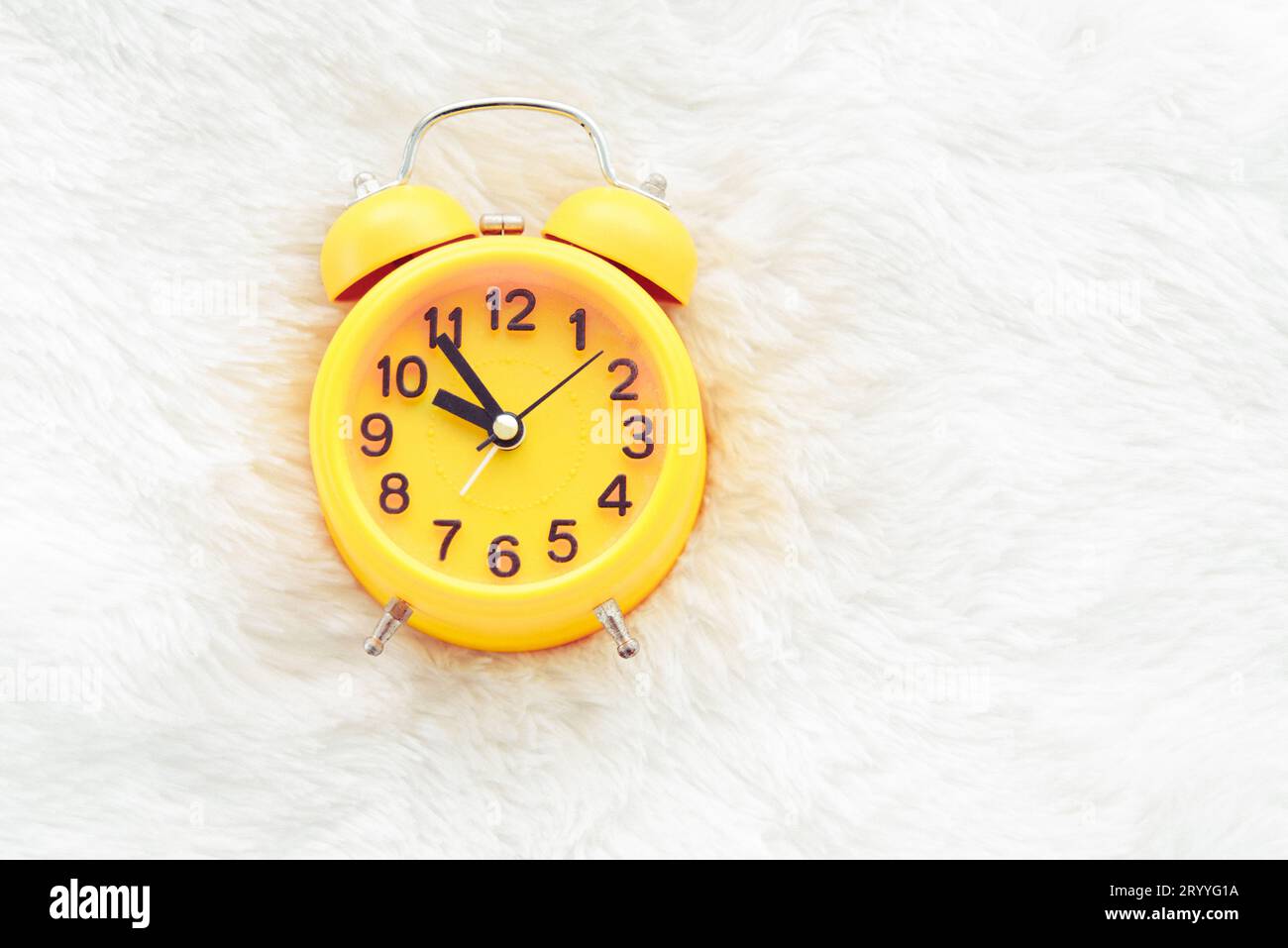Yellow alarm clock on white wool. Late and Lazy time concept. Morning ...