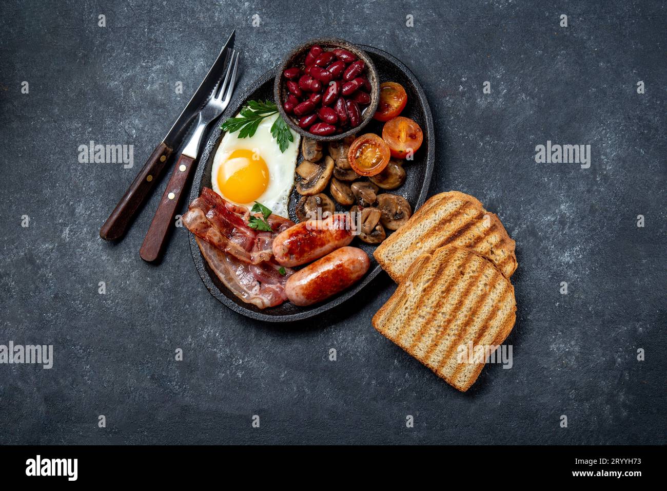 Full fry up English breakfast with fried eggs, sausages, bacon, black ...