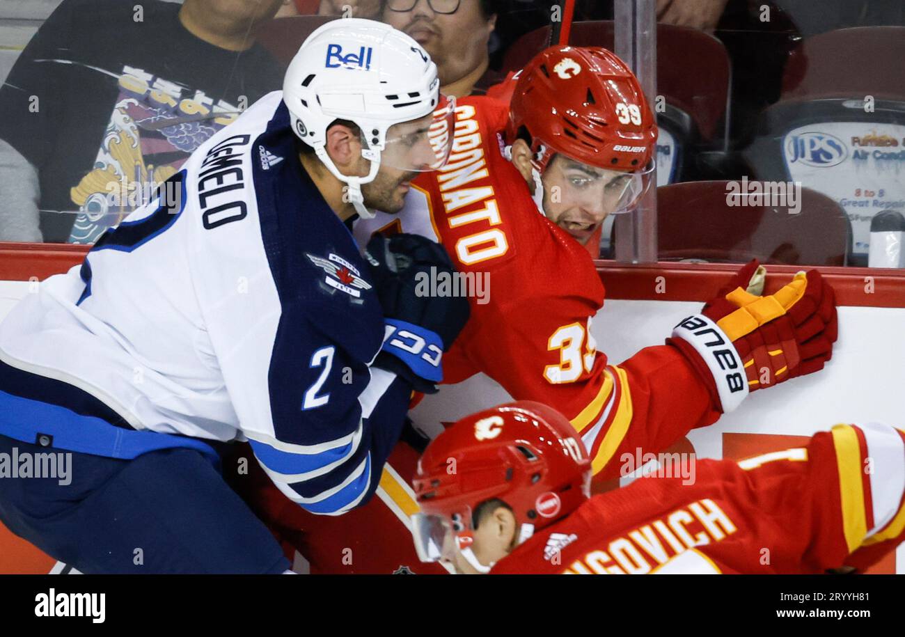 Winnipeg Jets defenseman Dylan DeMelo, left, checks Calgary Flames ...
