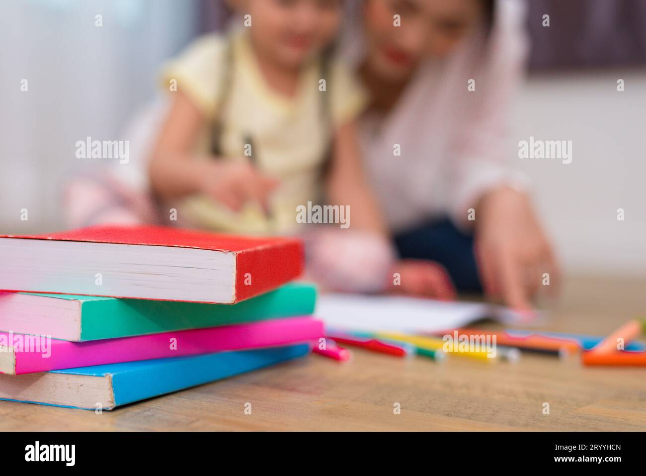Close up of books on floor with mom and kids background. Back to school ...