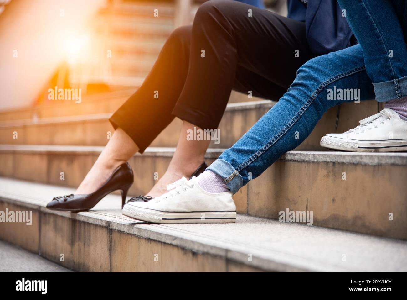 Close up of two woman legs. Friend are talking together on stair ...