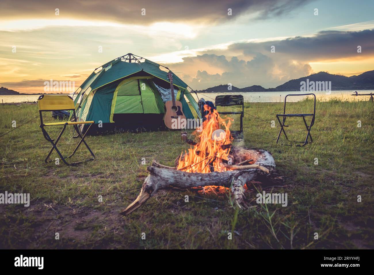 Camping tent with bonfire in the green field meadow, Lake and mountain ...