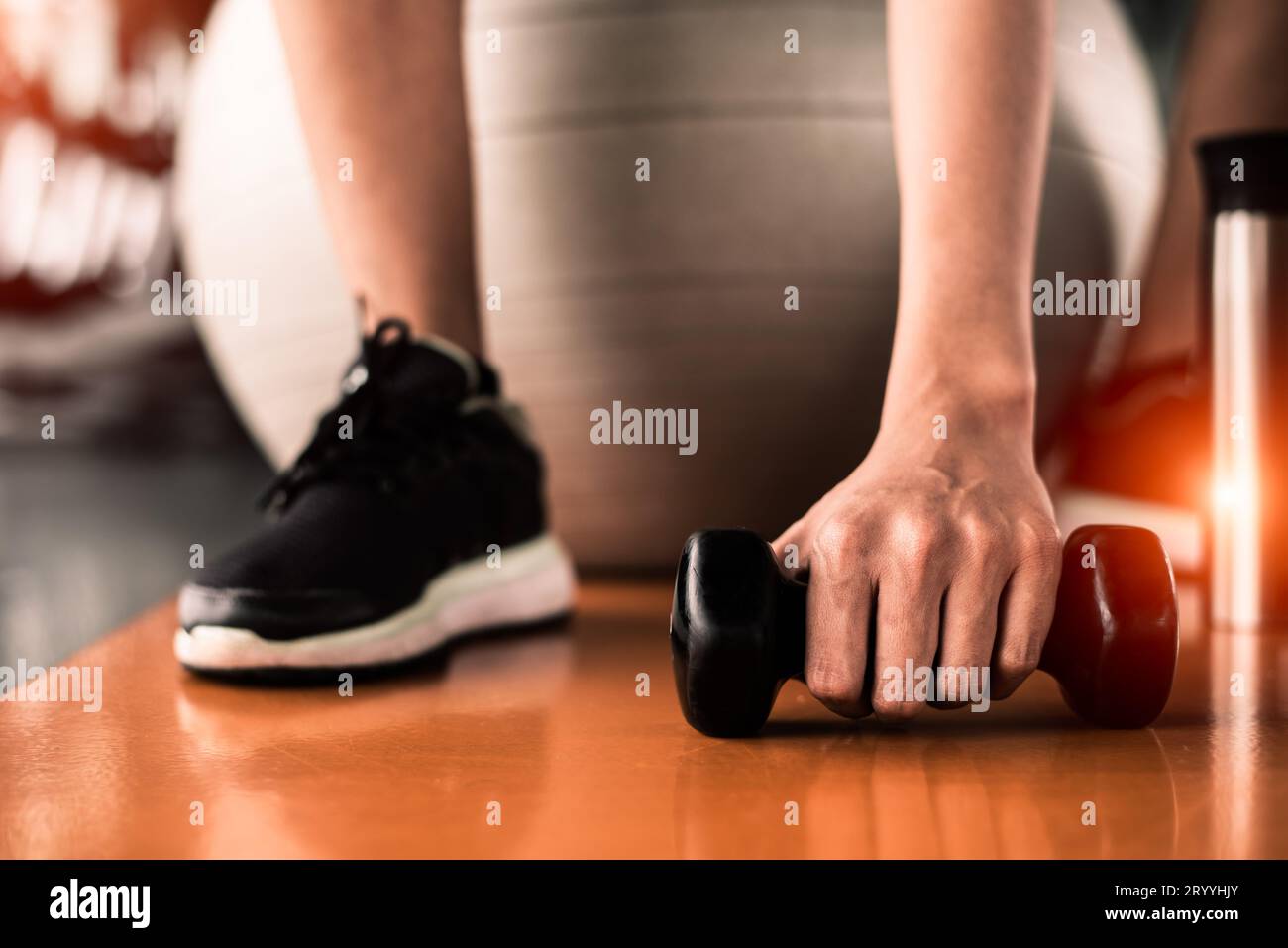 Close up of sport woman sitting on yoga ball and grab dumbbell on floor ...