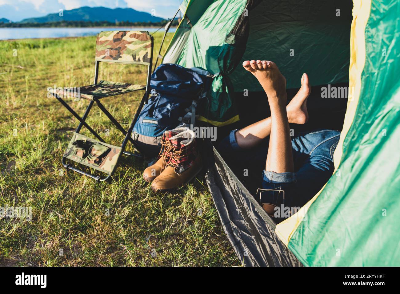 Close up of woman legs relaxing in camping tent with mountain lake and ...
