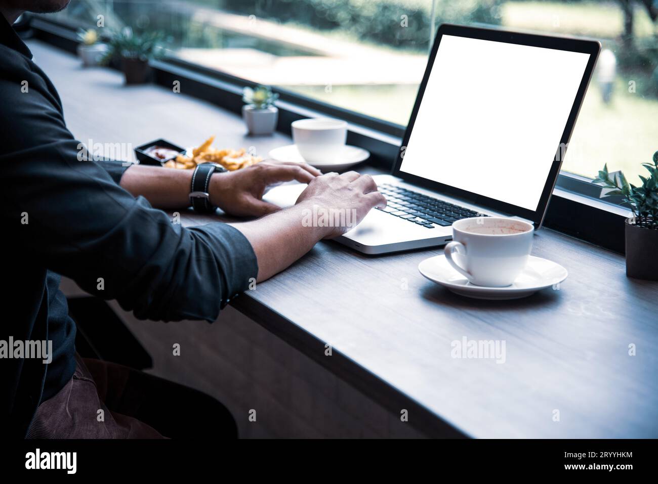 Side view of businessman using the laptop with blank white screen at ...
