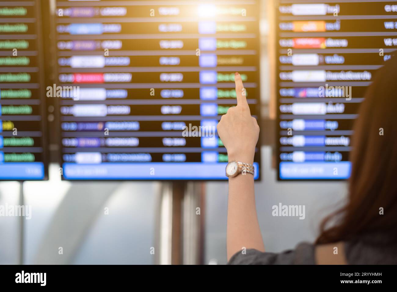 Back view of woman looking for flights from flight schedule in airport ...