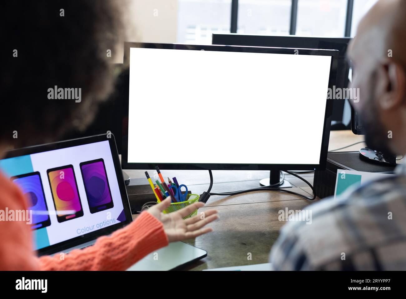 Rear view of diverse male and female designers discussing at computer ...