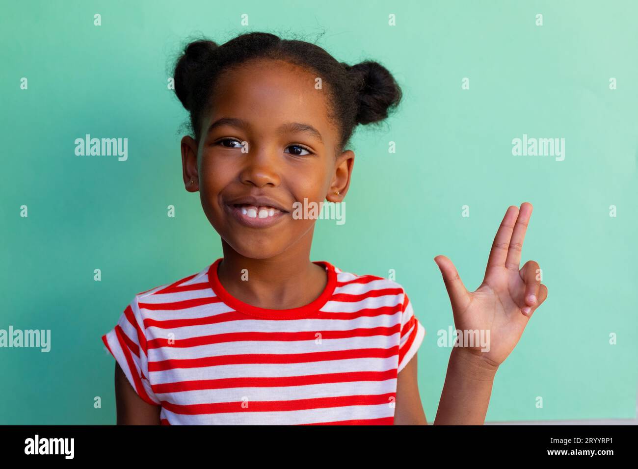 African american schoolgirl oing sign language with hand over blue ...