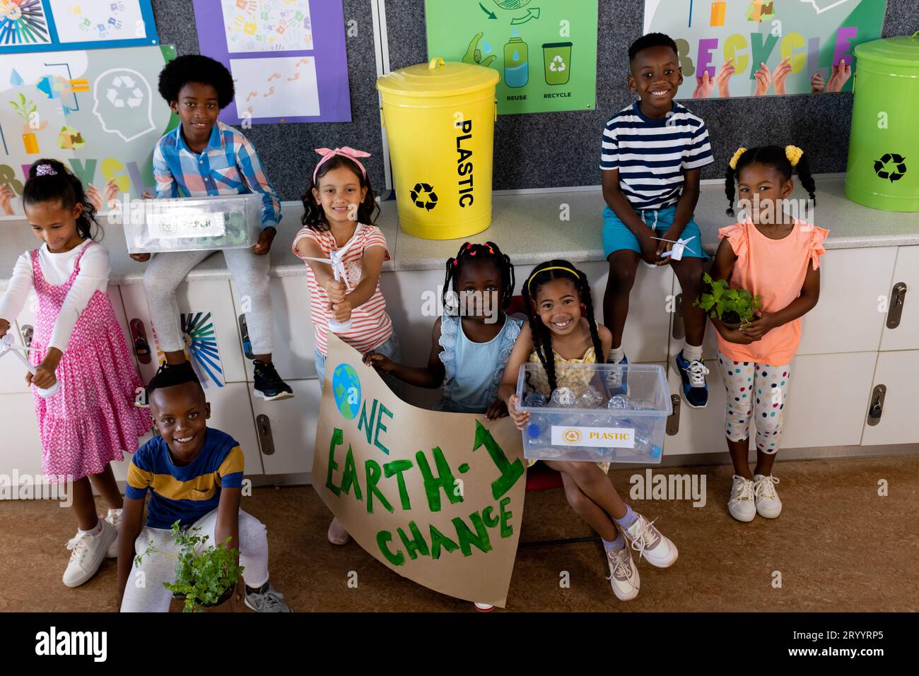 Portrait of happy diverse children with ecology items and plants in ...