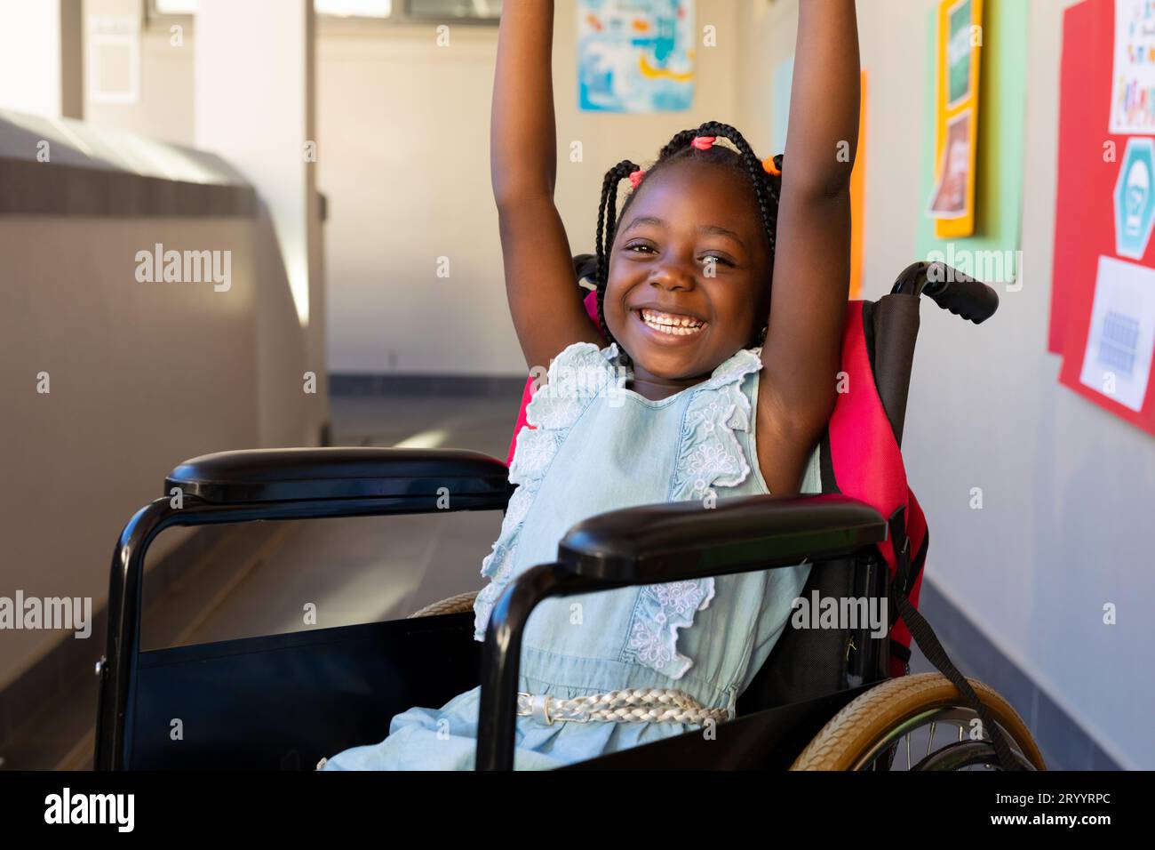 Portrait of african american schoolgirl sitting in wheelchair and ...