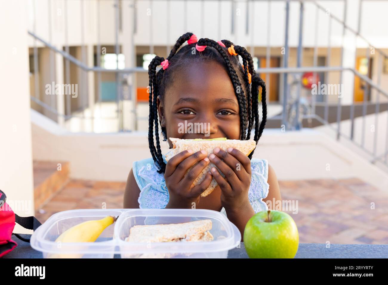 Happy african american schoolgirl having healthy lunch eating sandwich ...