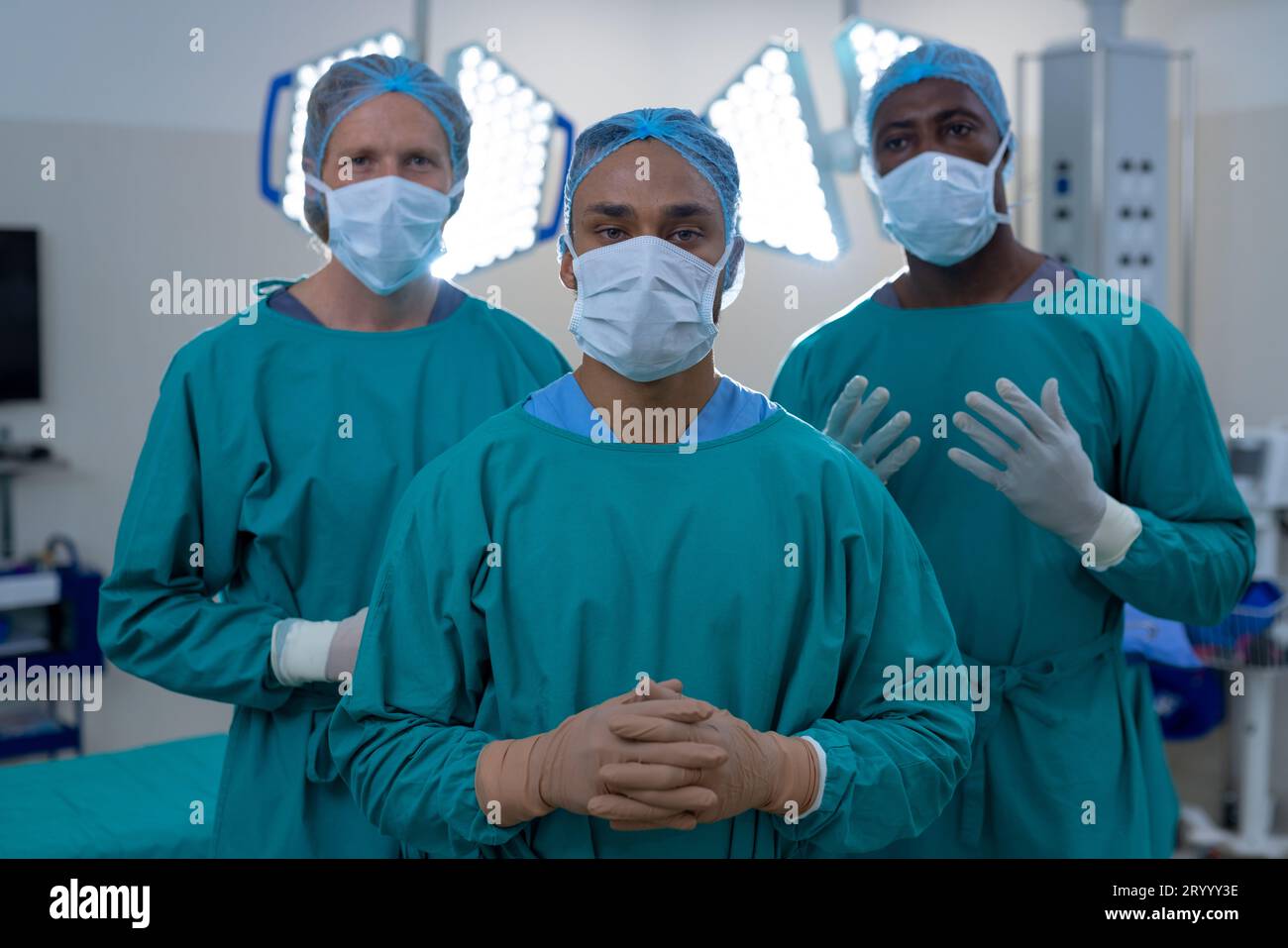 Portrait of diverse male surgeons wearing surgical gowns in operating ...