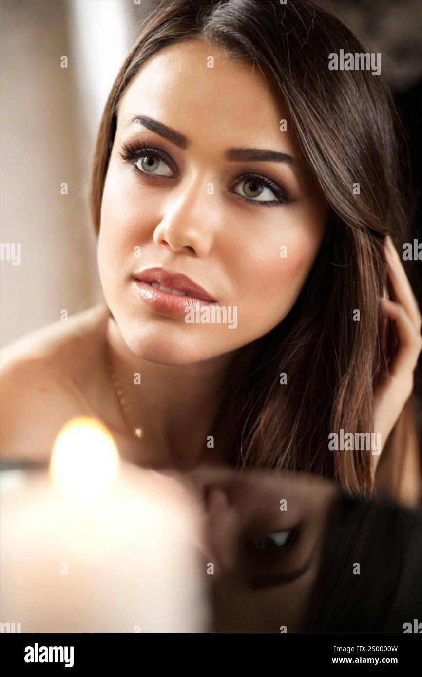 Relaxed woman smelling a lighted scented candle in the night at home ...
