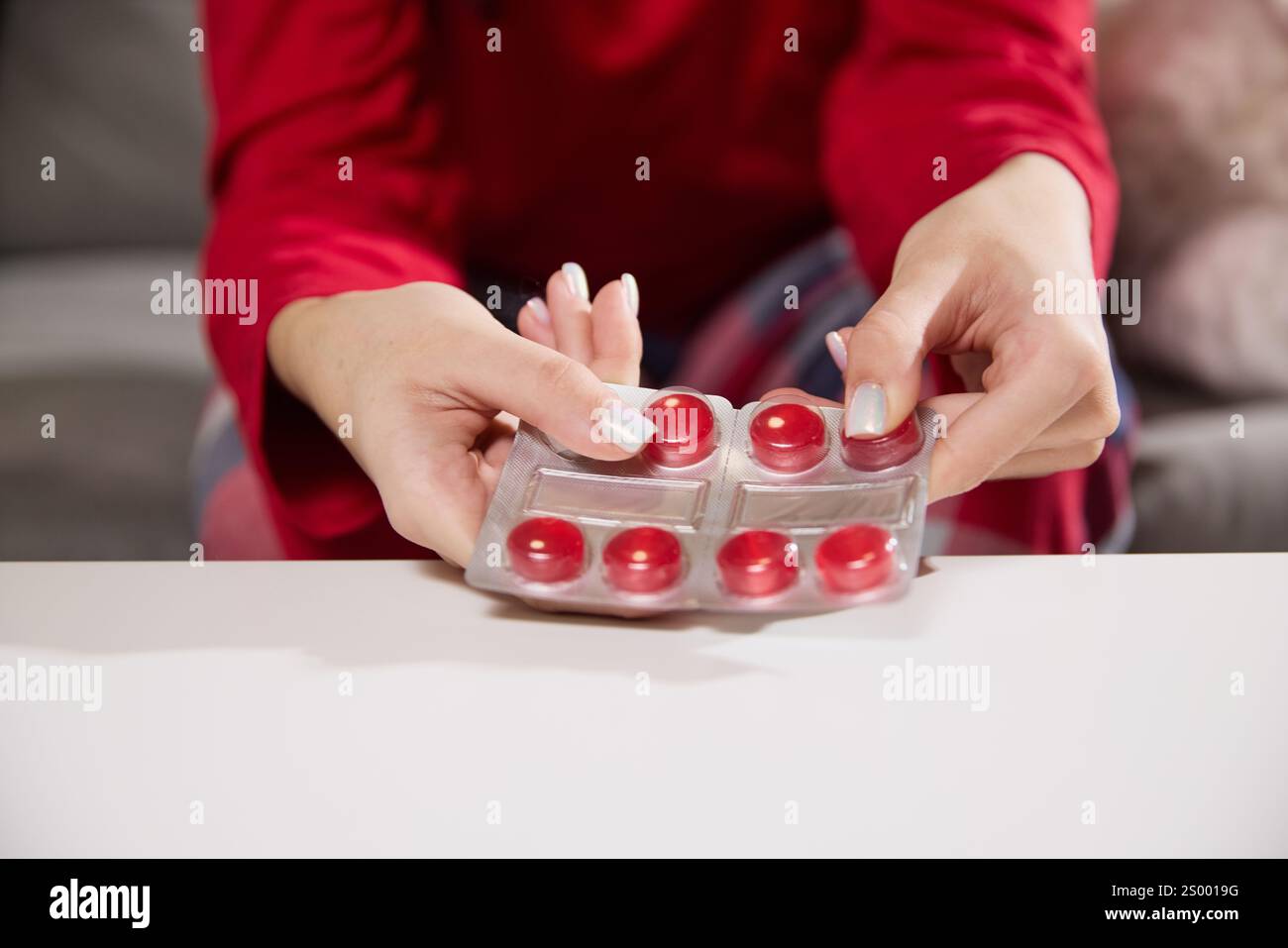 Person in red outfit holding red lozenges in blister pack, carefully ...
