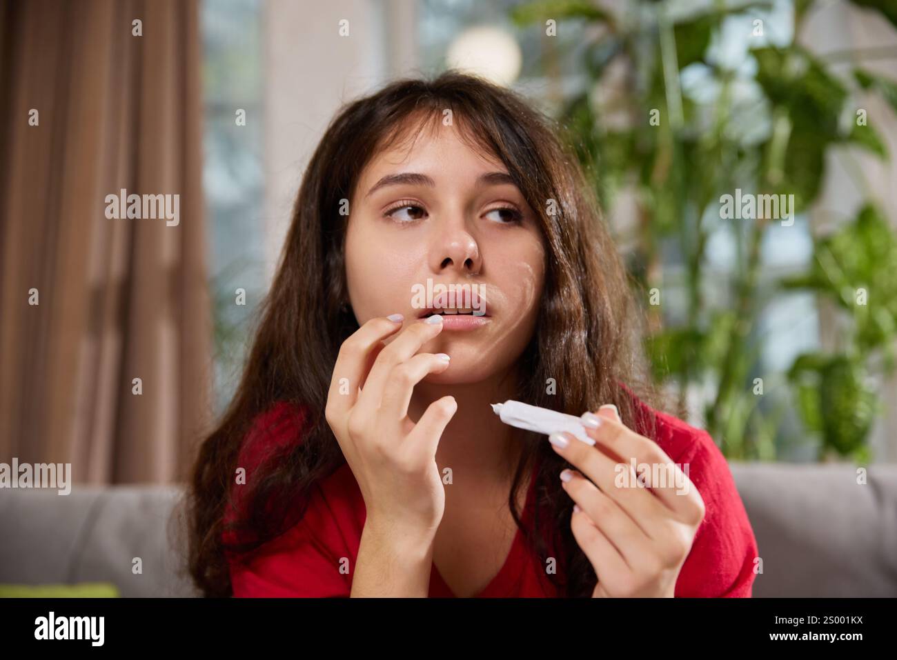 Close-up portrait of woman applies ointment to her lips with focused ...