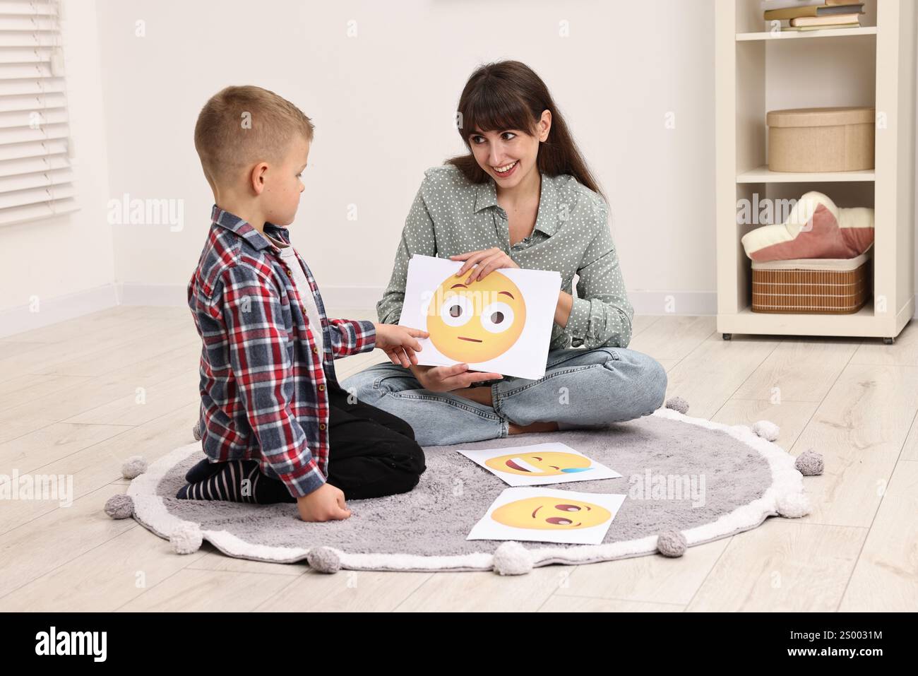 Autism therapy. Little boy choosing emoticon with smiling psychologist ...