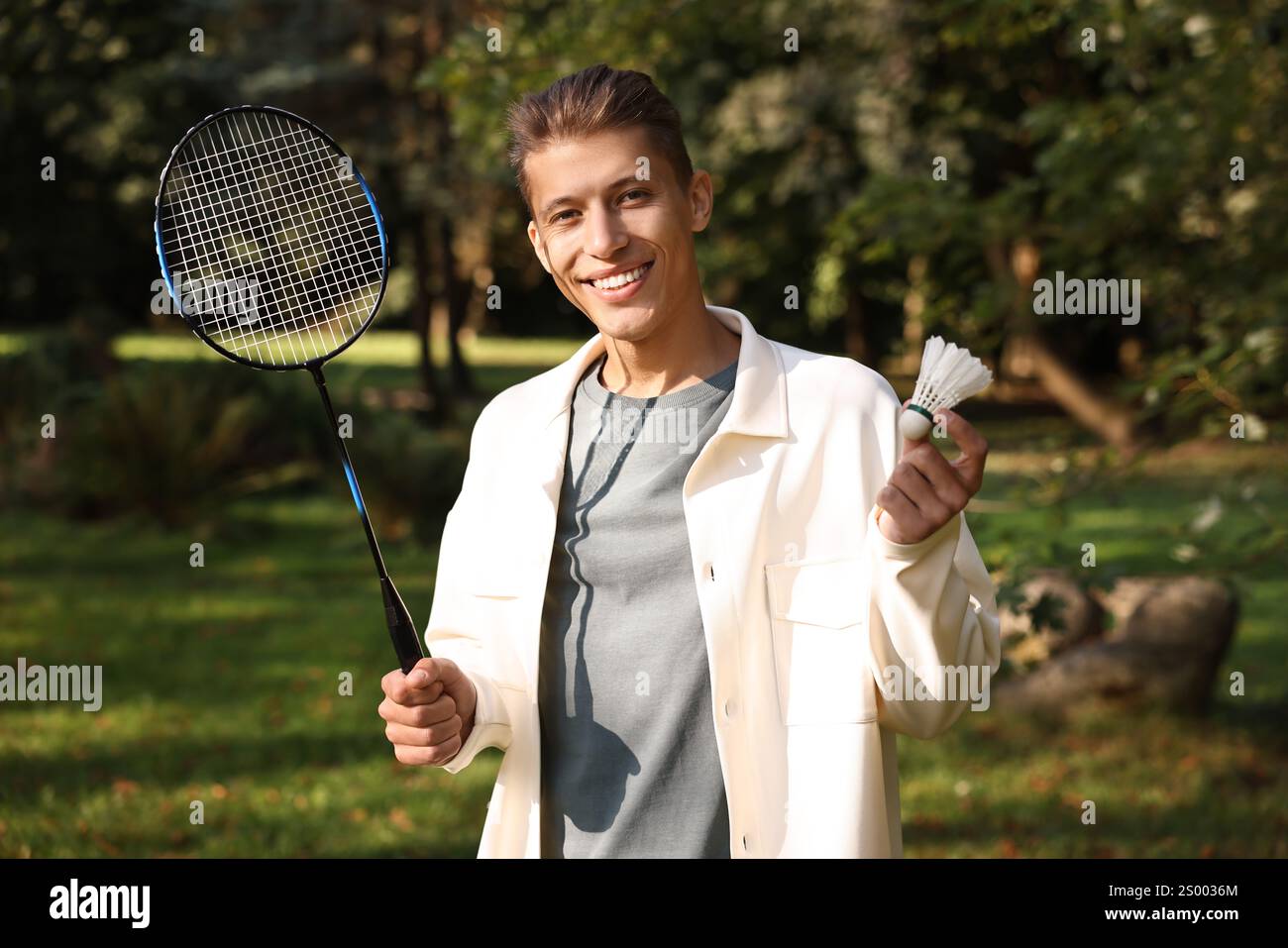 Happy young man with badminton racket and shuttlecock in park Stock ...