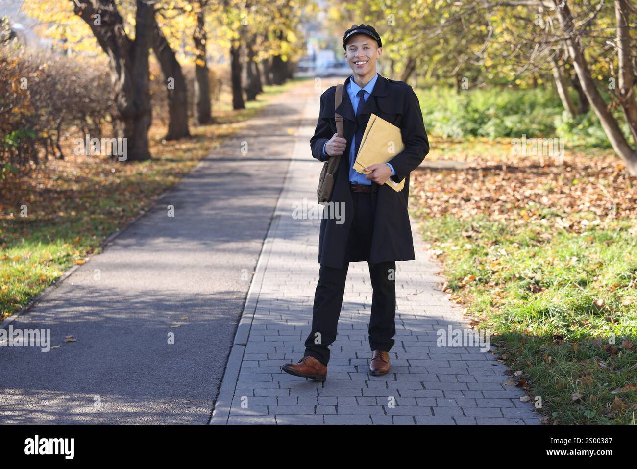 Happy postman with bag and envelopes outdoors Stock Photo - Alamy