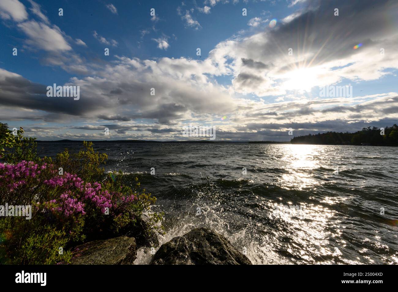 The waves and water of Lake Winnipesaukee pushing up againd the bright ...