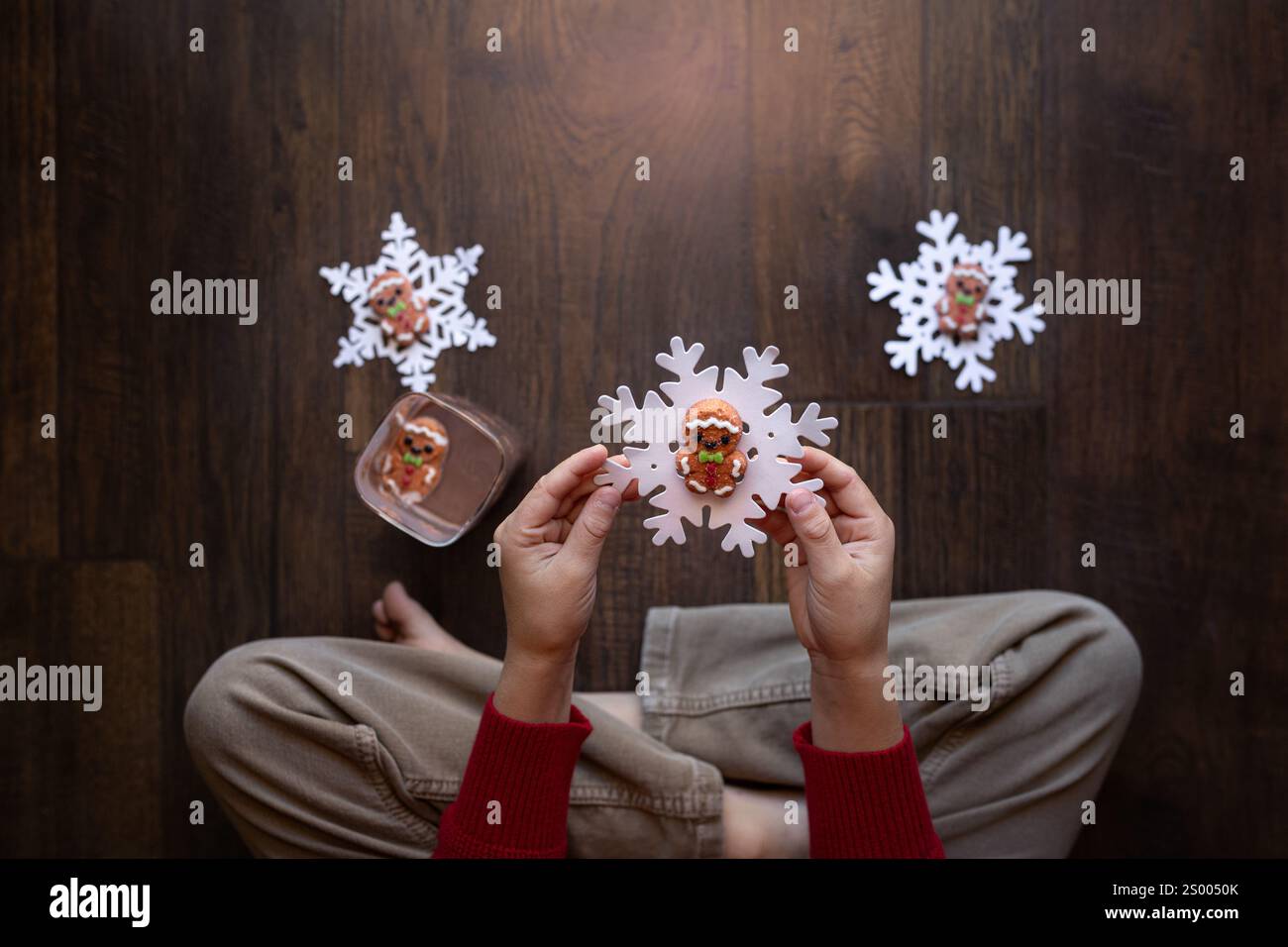Child holding a snowflake cutout with gingerbread man on wooden floor ...