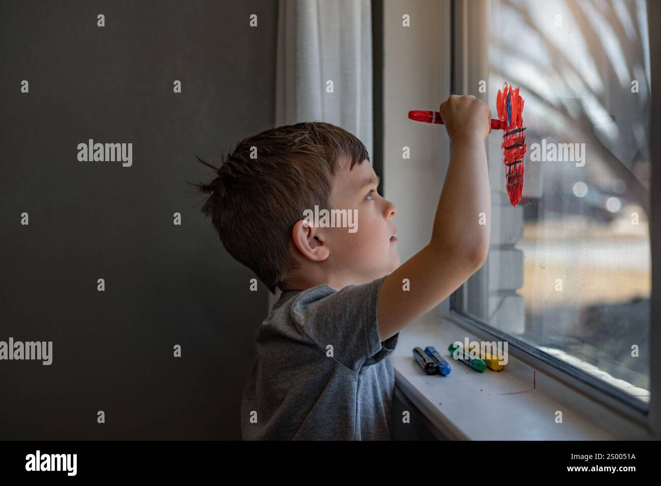 boy drawing on window with crayons with sunlit background Stock Photo ...