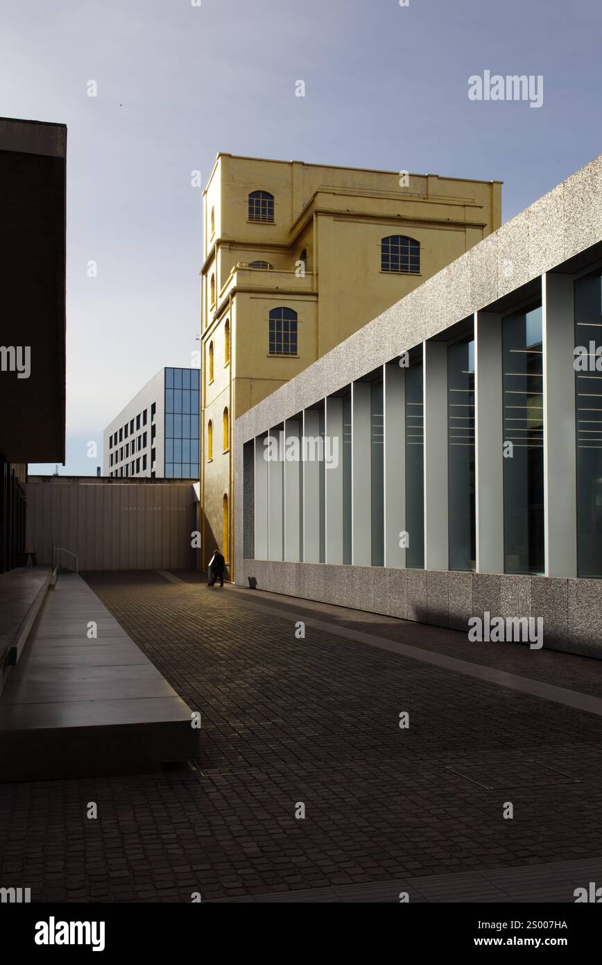 An urban courtyard features a striking contrast of modern glass walls ...