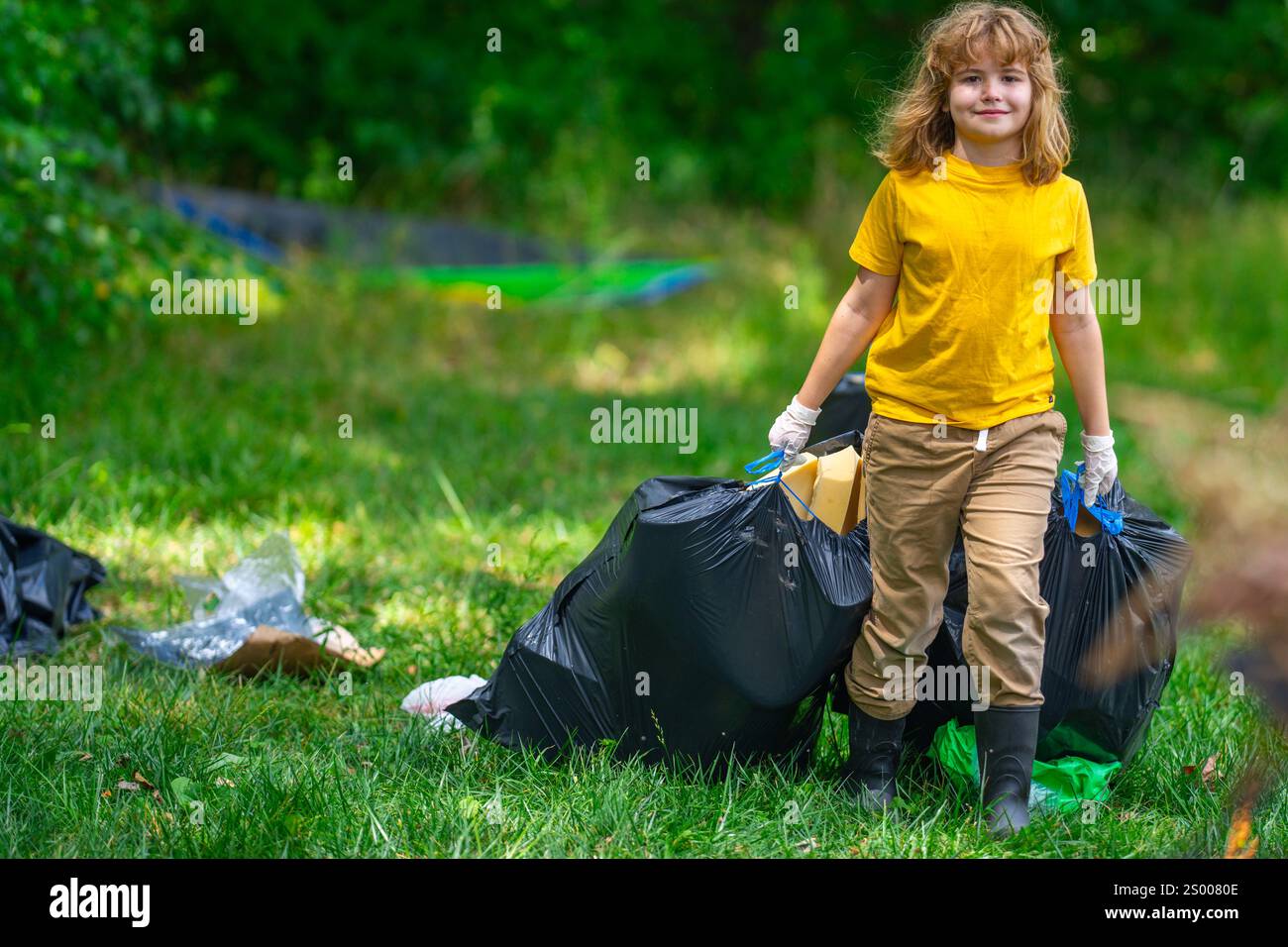 Environment plastic pollution. Volunteer kid collecting trash in the forest and holding a ...