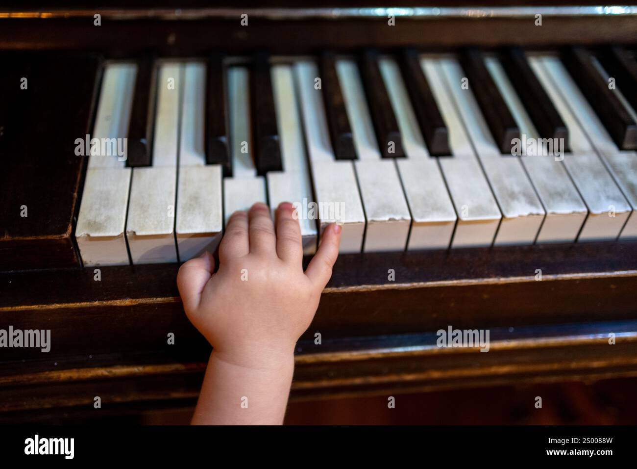 Child's hand gently pressing piano keys, exploring music indoors Stock ...