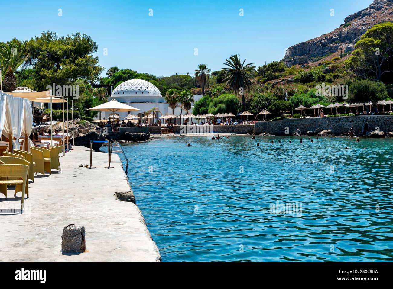 Rhodes, Greece - July 6, 2024: Lindos beach , sunbeds and clear water ...
