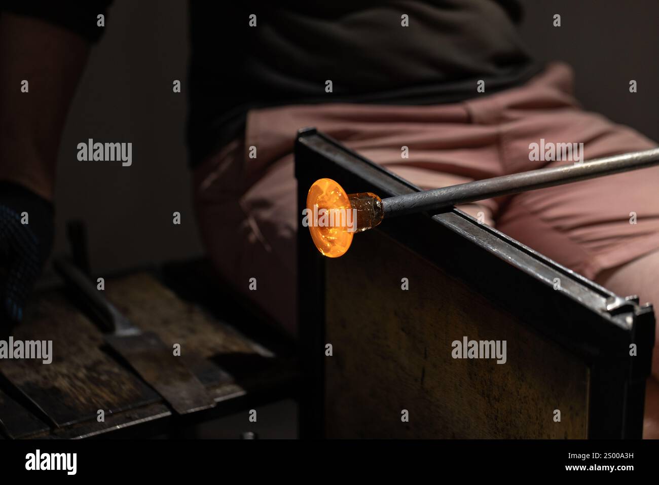 Molten glass rotates on blowing pipe at glass-blowing studio Stock ...