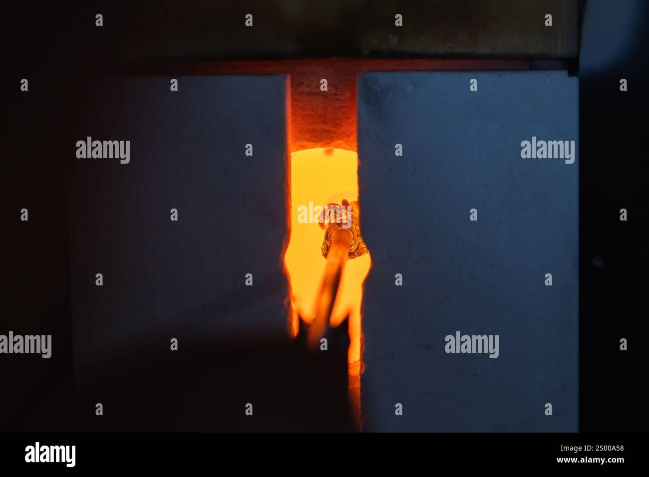 Glowing open furnace with molten glass on a blowpipe inside, glass ...