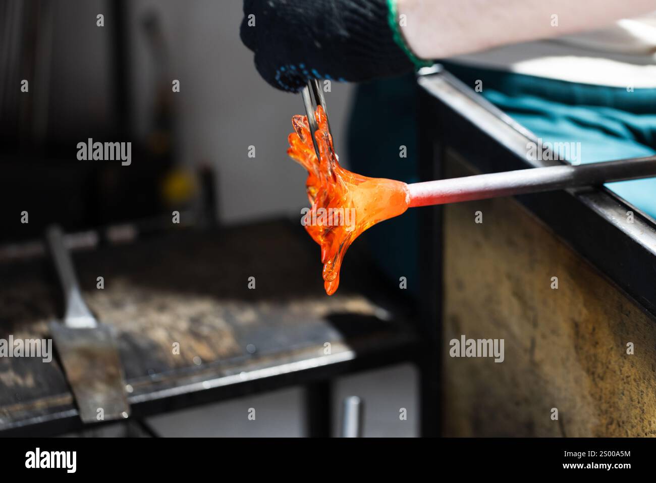 Molding molten glass into a flower shape, glass blowing workshop works ...