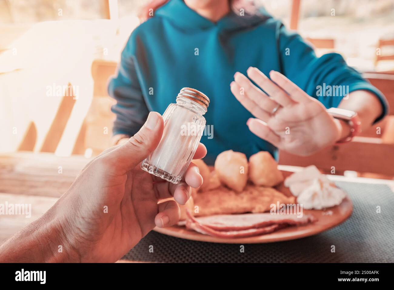 Woman refusing salt shaker offered by waiter, following a healthy diet ...