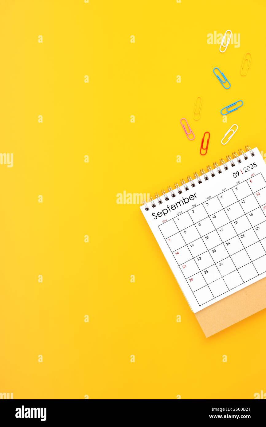 September 2025 desk calendar and paper clips on yellow color background ...