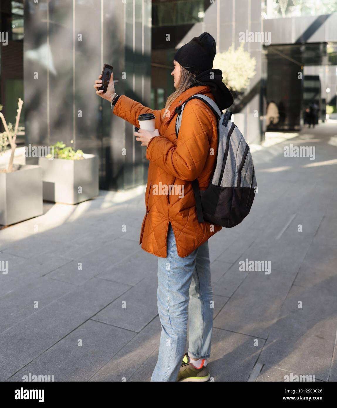 A young individual happily captures a cheerful selfie while holding a ...