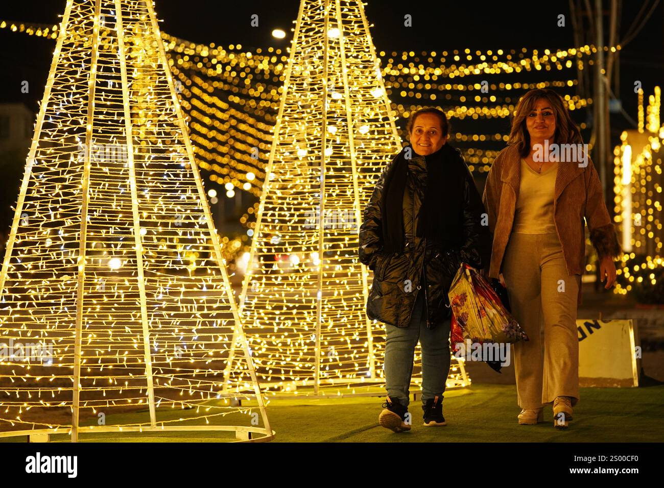 Christians walk through decorated streets in the town of Qaraqosh, also ...