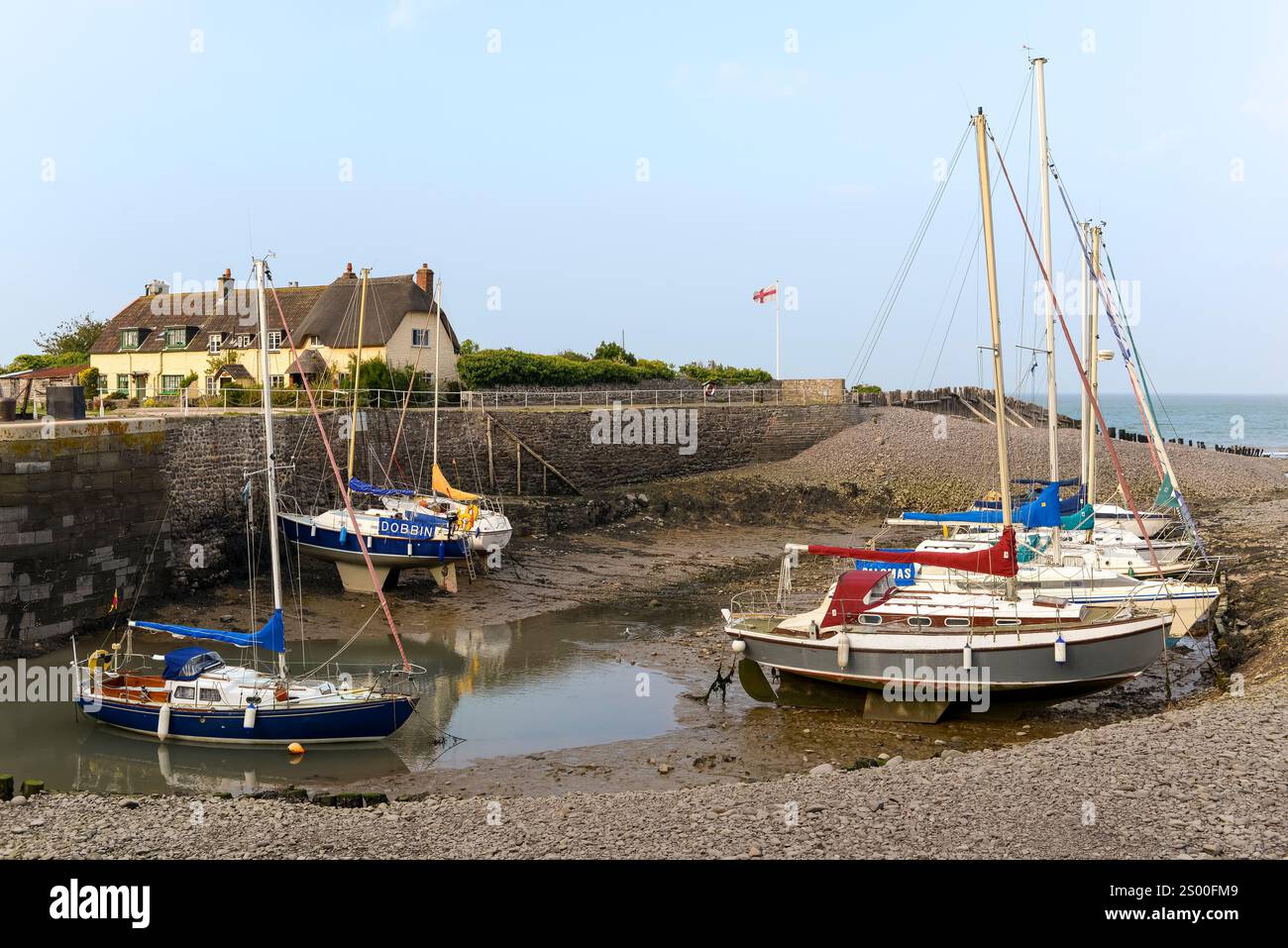 Porlock Weir, North Devon, UK. Boats at low tide and thatched cottages ...